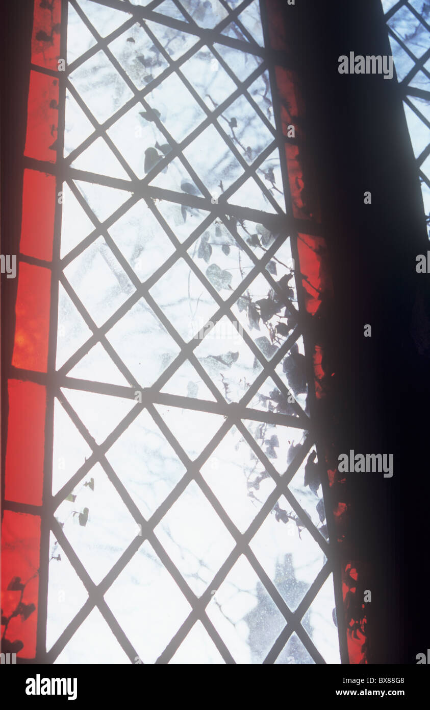 View through diamond-leaded plain window fringed with red stained glass ...