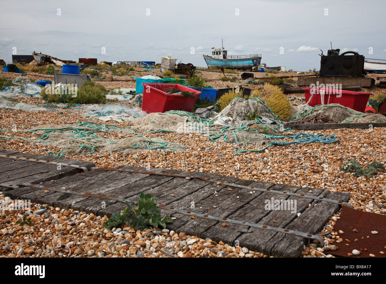 Shingle beach with discarded fishing nets and derelict boats at ...