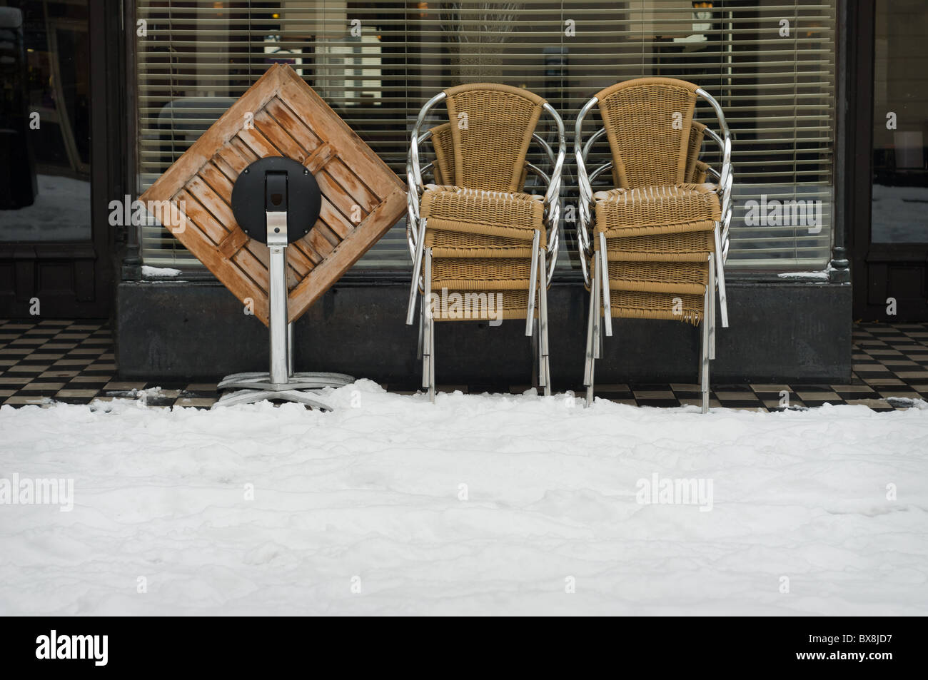 Tables and chairs stacked outside a cafe after an early winter snow ...