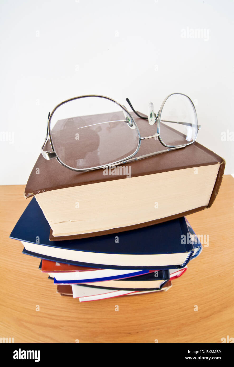 stack of open hardcover books and bifocal reading glasses on wooden ...