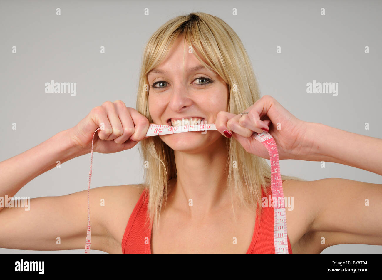Young woman with tape measure between her teeth Stock Photo - Alamy