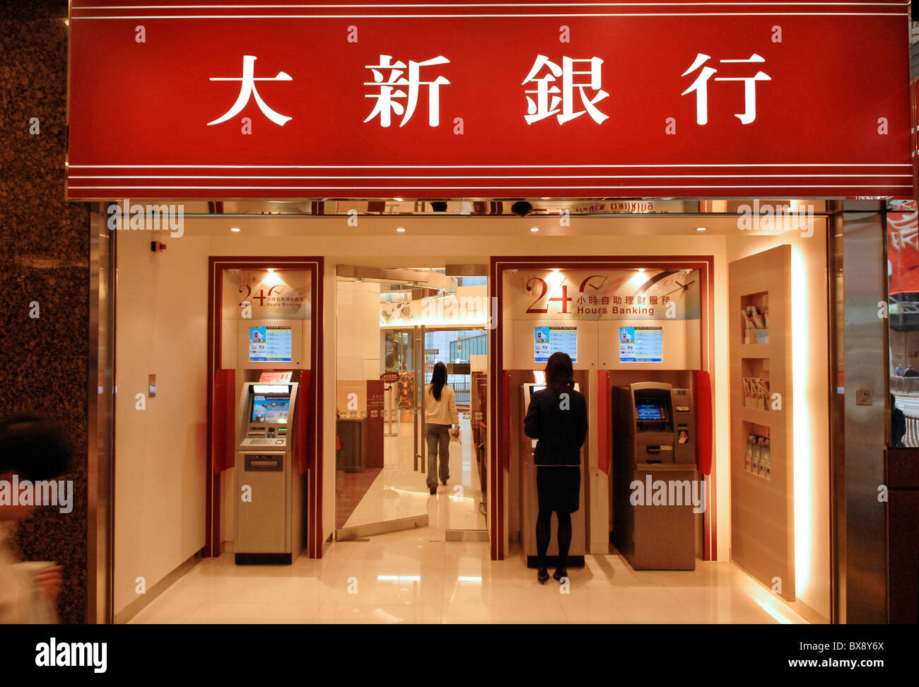 A Chinese woman using cash machines in ATM cash point at the entrance ...