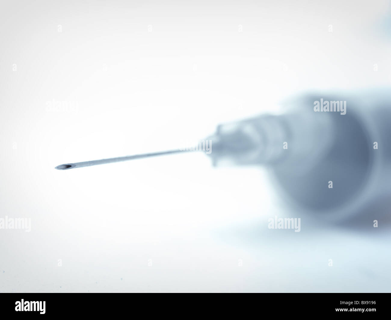 syringe over white background, blue toned,selective focus on the needle ...