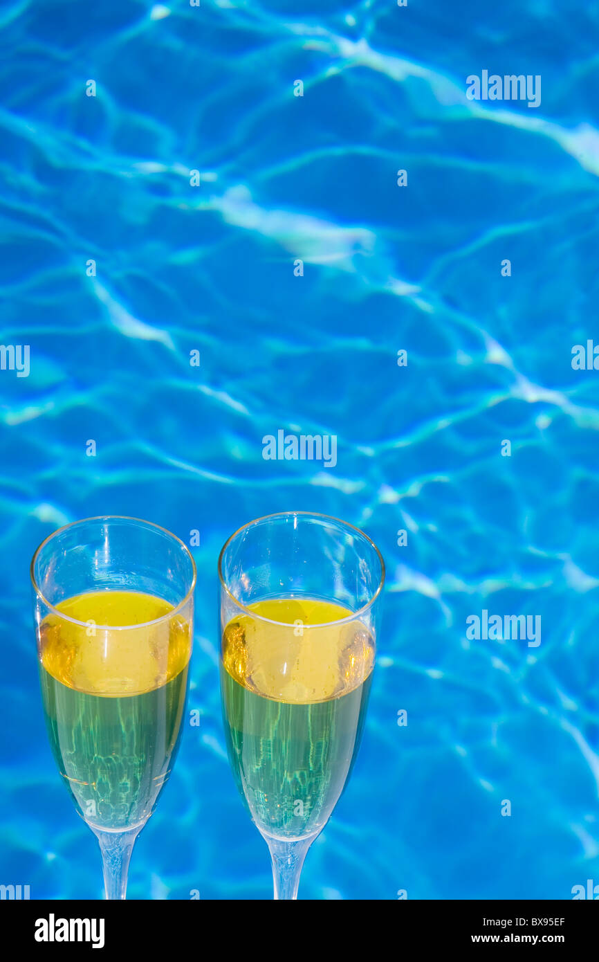 Two champagne glasses in front of a sparkling blue swimming pool Stock ...