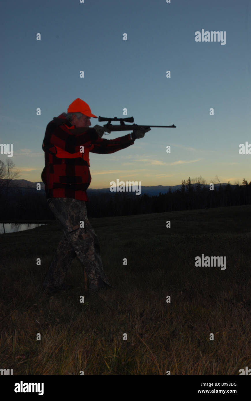 A hunter takes aim just before the end of shooting hour near dusk Stock ...