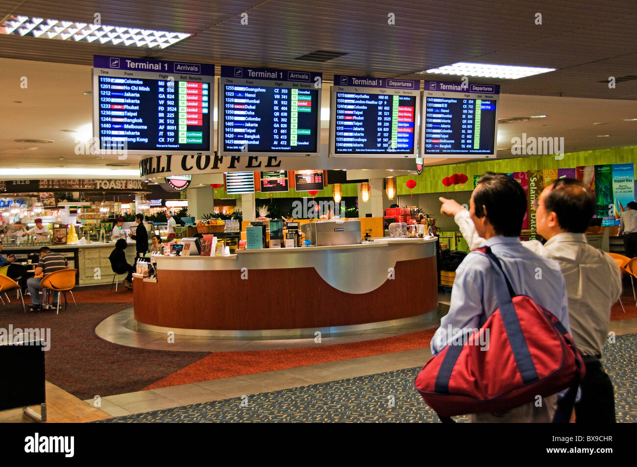 Two Asian men viewing airplane time departure and arrival schedules on ...