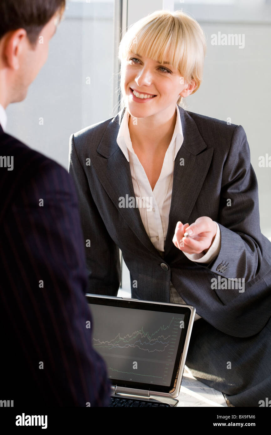 Portrait of business partner talking to her colleague in the office ...