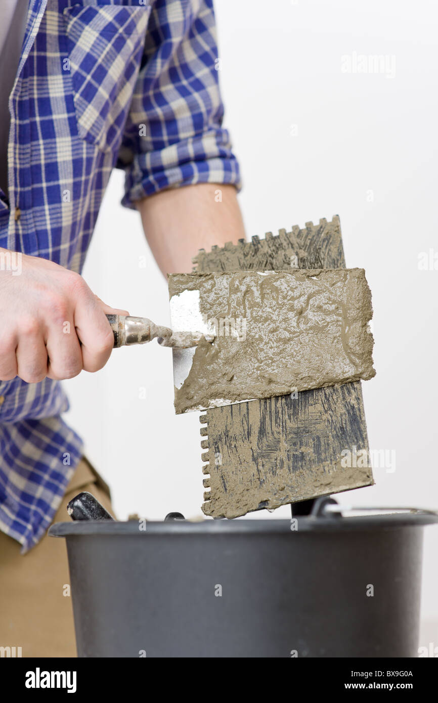 Home improvement, renovation - handyman laying tile, trowel with mortar ...