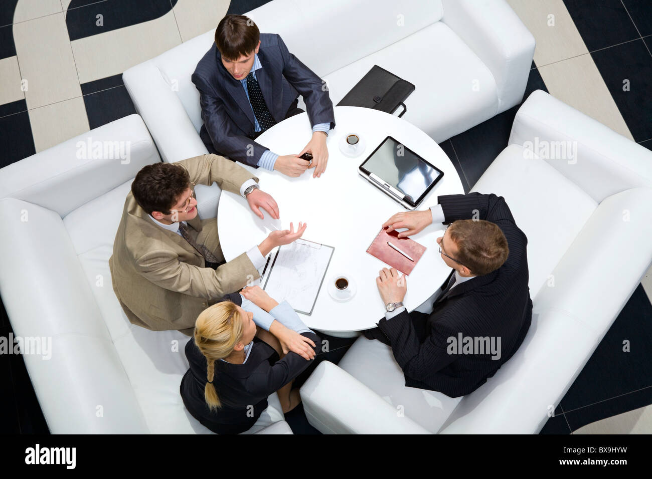 Portrait of businesspeople sitting around at the table and discussing ...