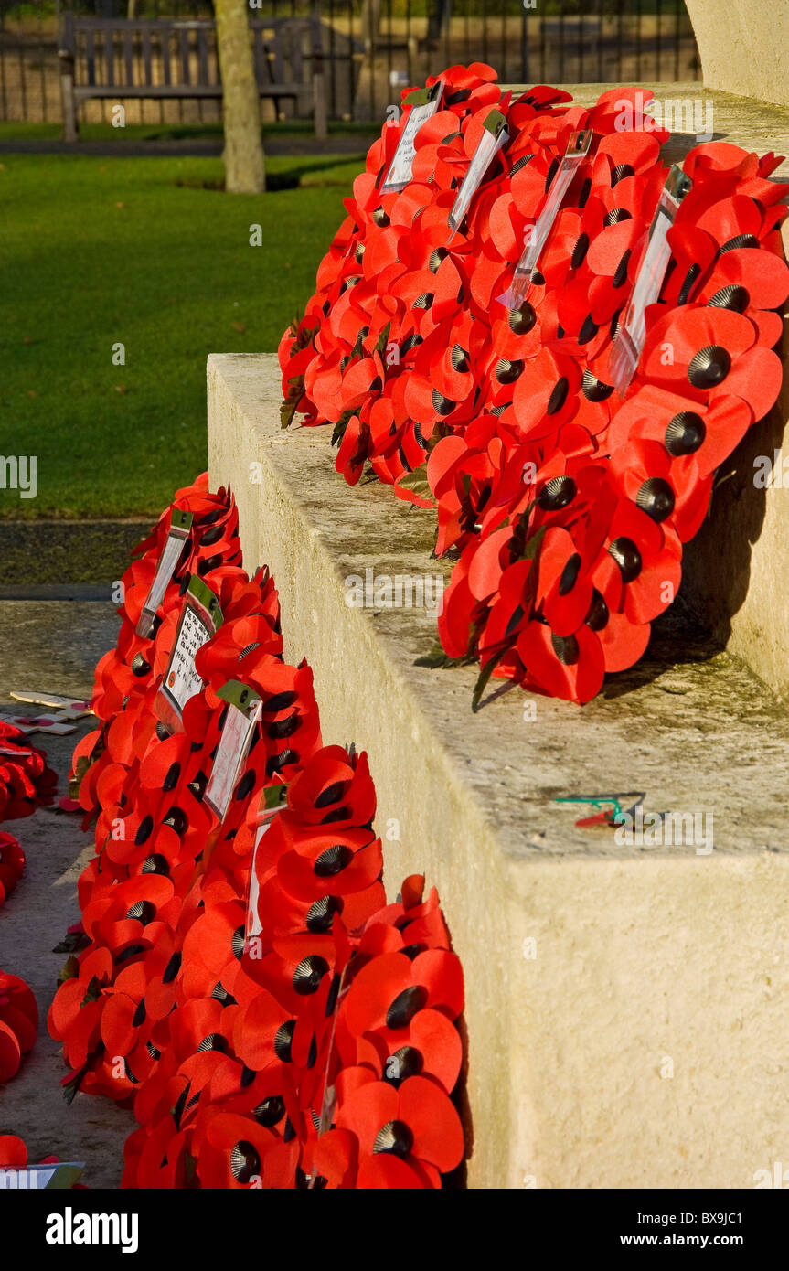 Close up of red poppy wreaths arranged at the base of war memorial for ...
