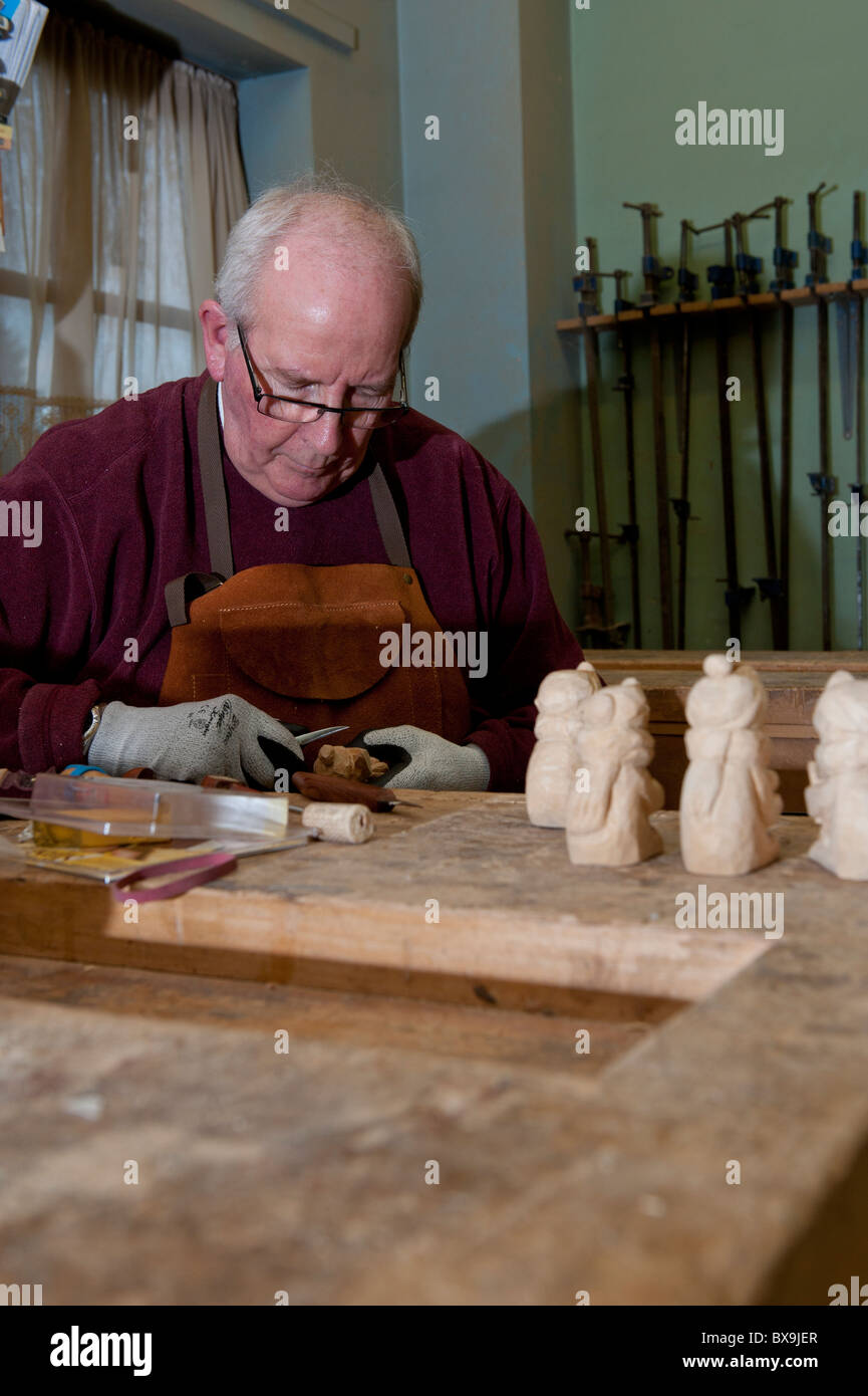 Retired male carving wooden creatures for Christmas in a woodworking ...