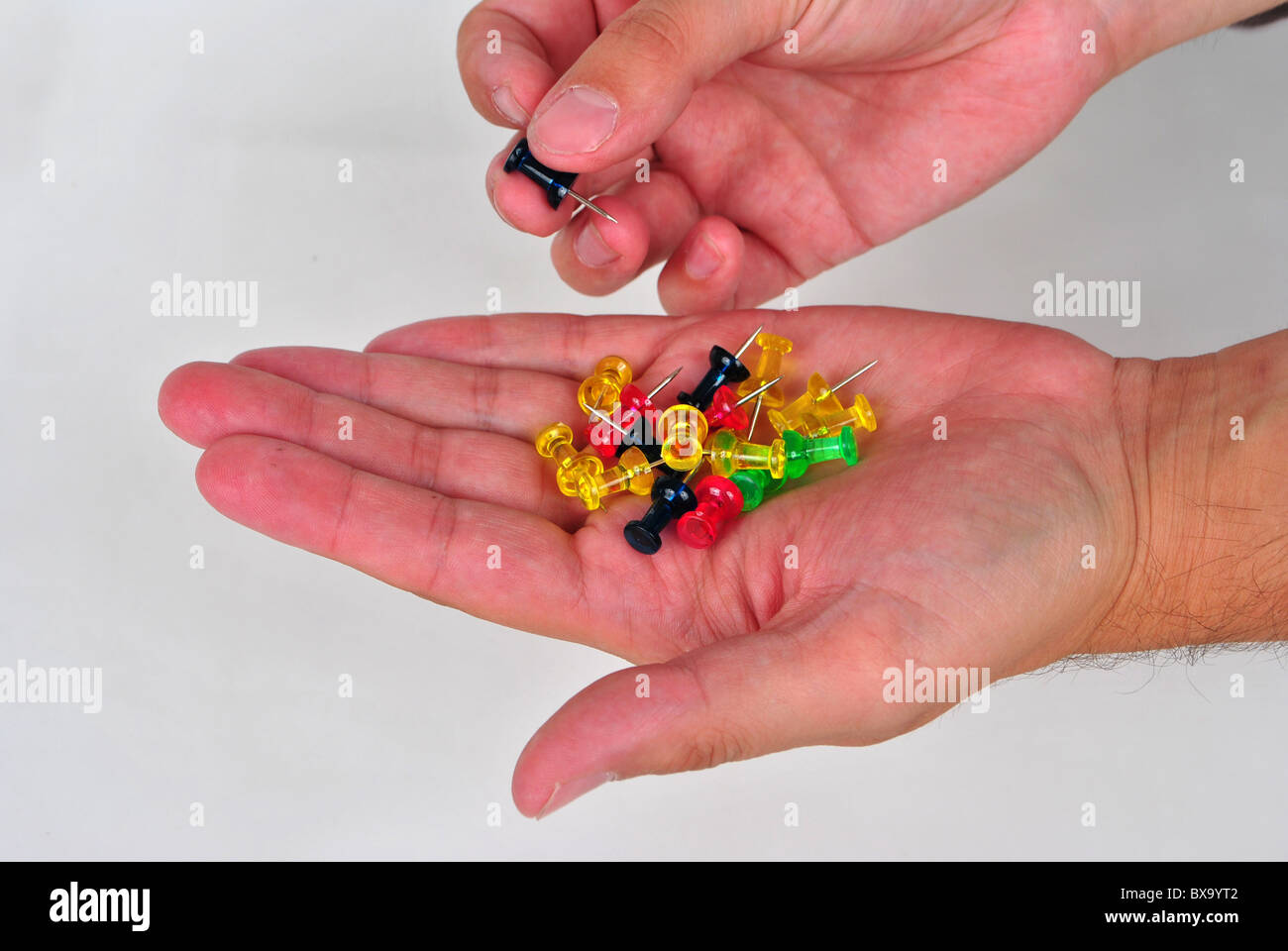 colored pins in blue yellow and red hand Stock Photo - Alamy