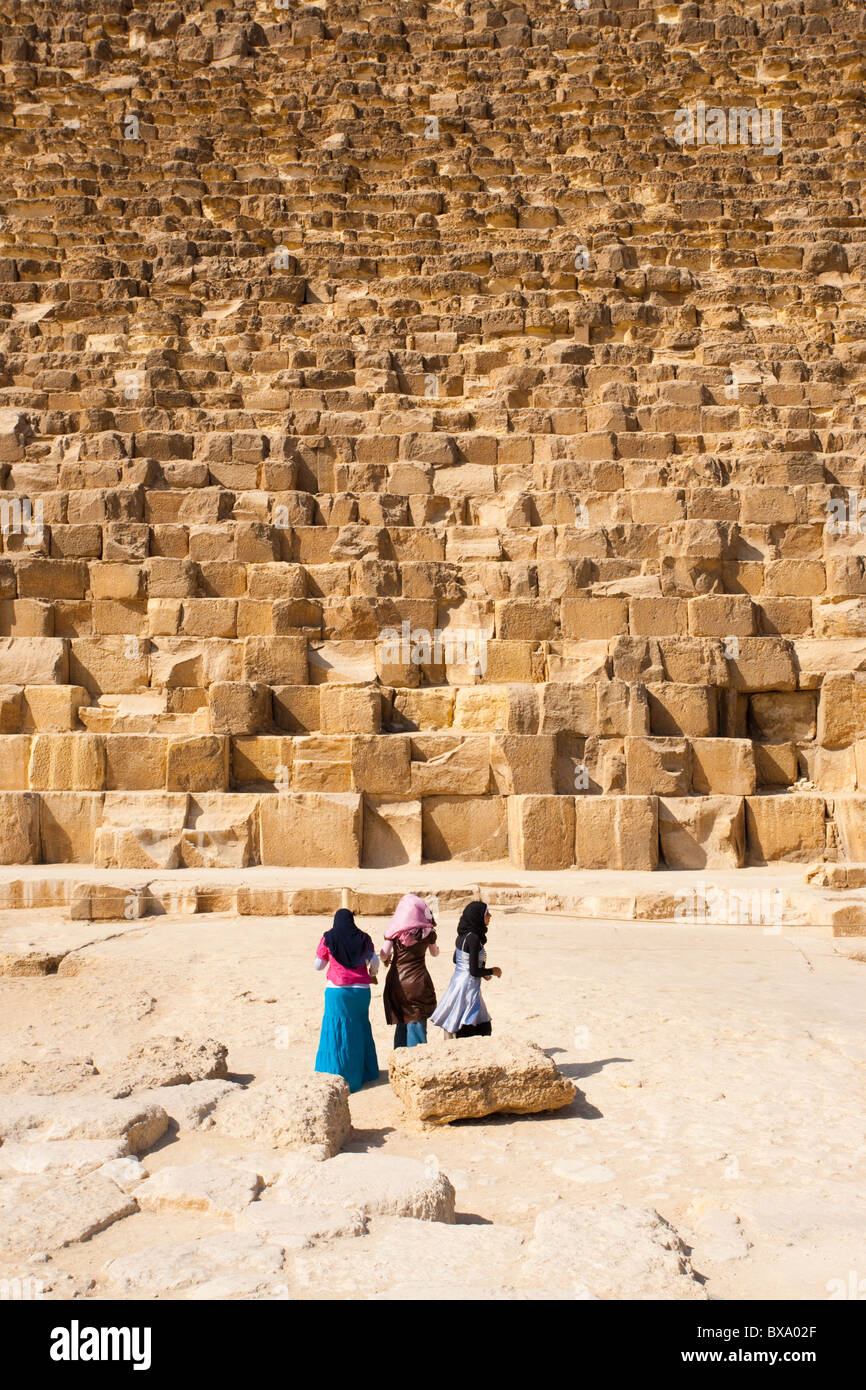 Egyptian girls wander around the base of the largest of the Great ...