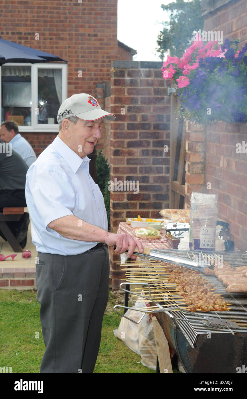 Elderly White man cooks on large Garden Barbecue Stock Photo - Alamy