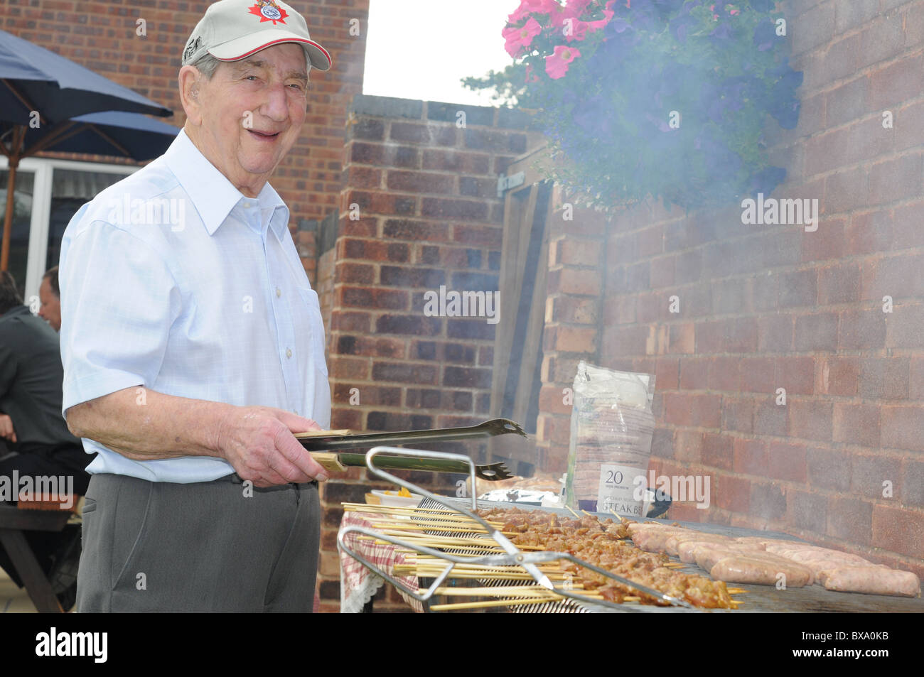 Elderly White man cooks on large Garden Barbecue Stock Photo - Alamy