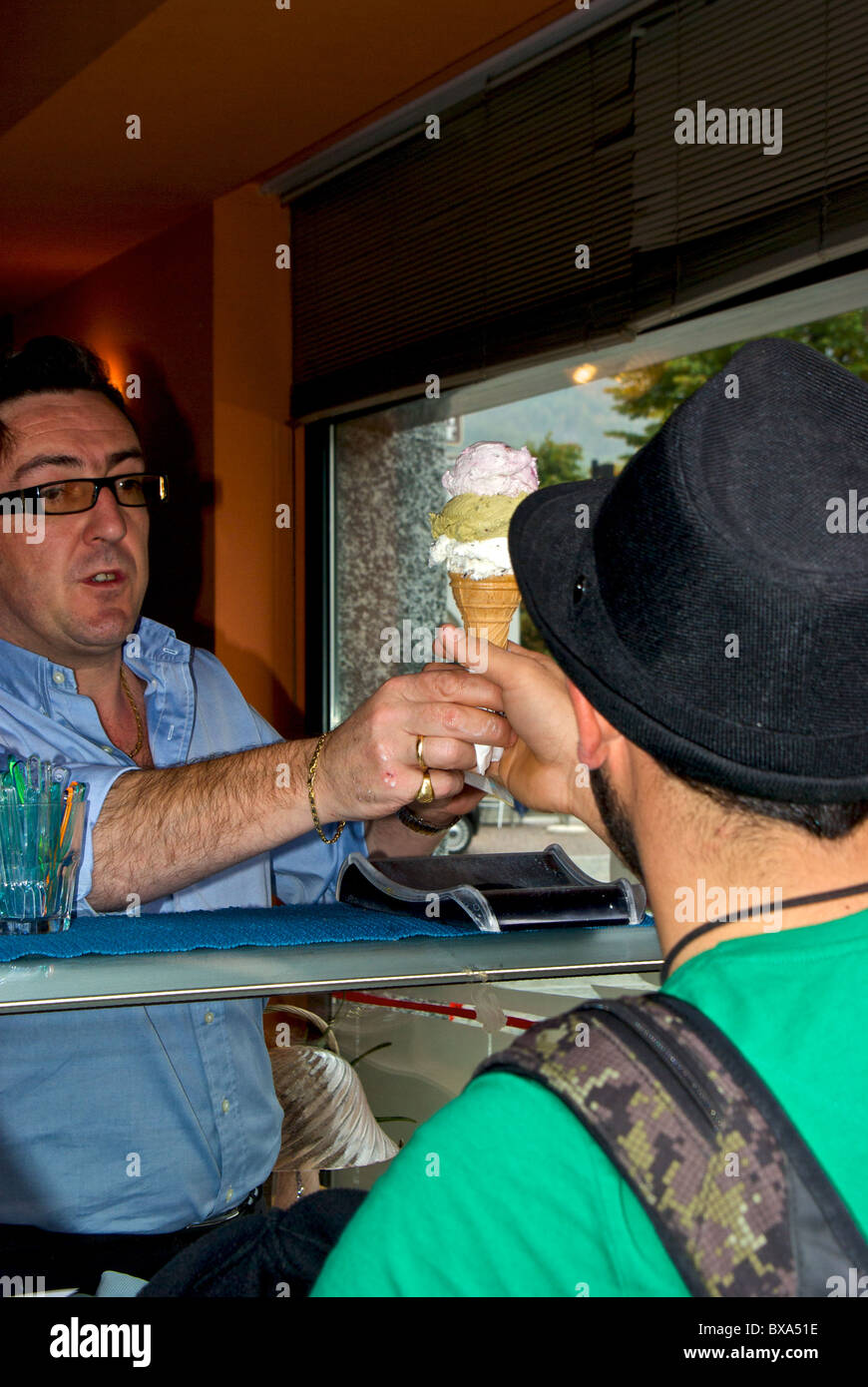 Proprietor outdoor Italian gelato ice cream stand handing big triple ...