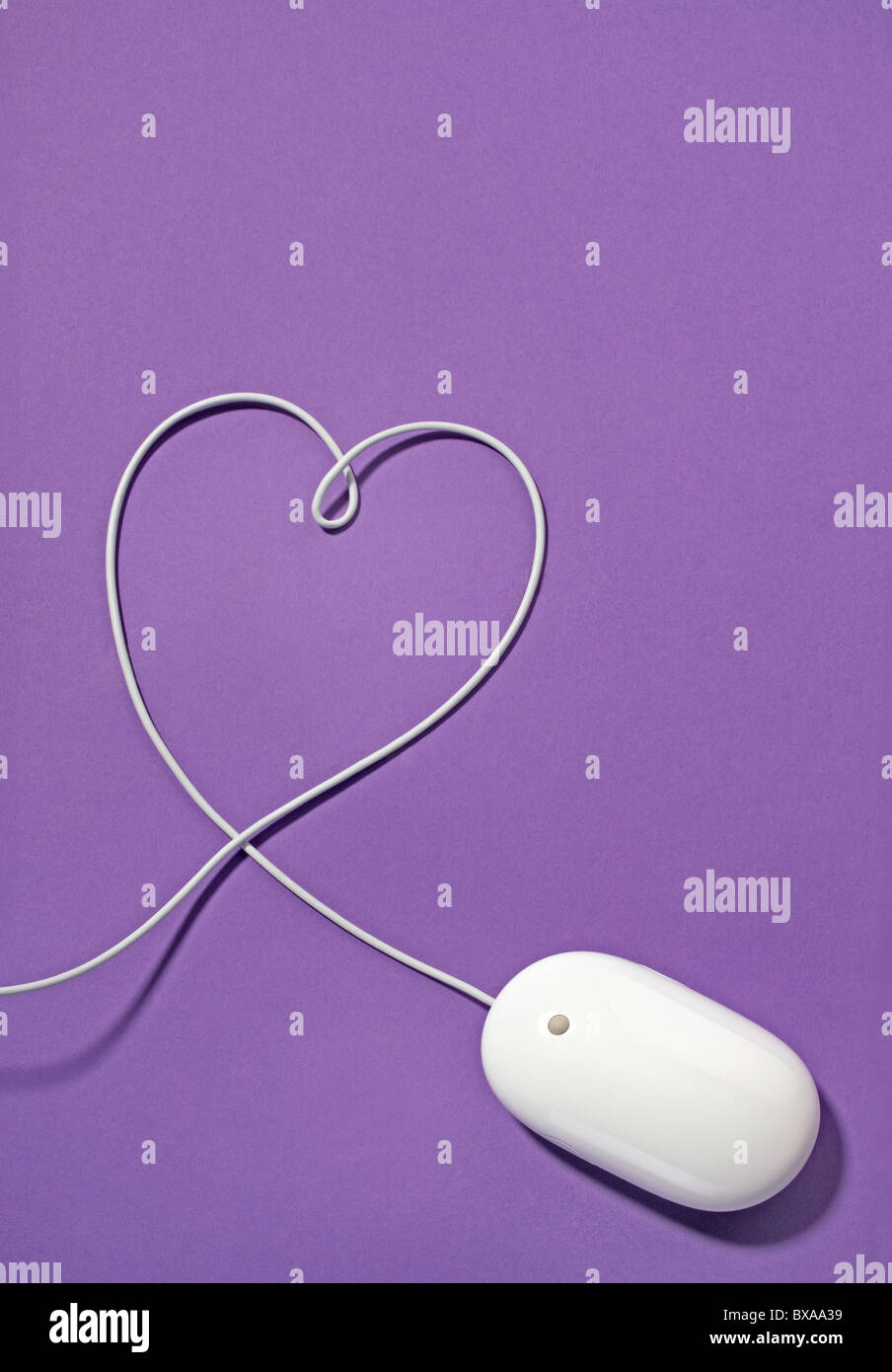 apple mac mouse with wire shaping a heart on purple background Stock ...