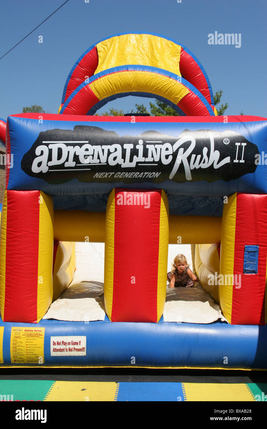 Young girl finishes a slide inside an Adrenaline Rush inflatable bounce ...
