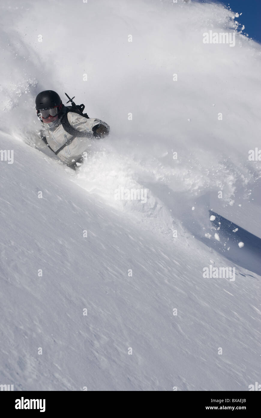 A snowboarder making a turn towards the camera in deep powder snow ...