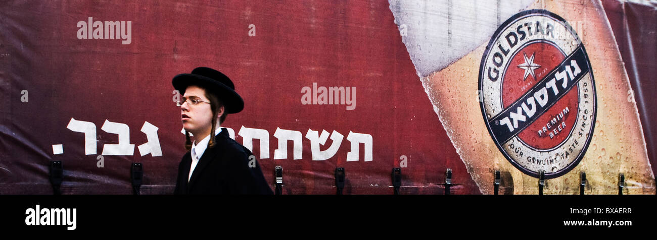 An Orthodox Jewish man standing by an advertisement for a famous ...