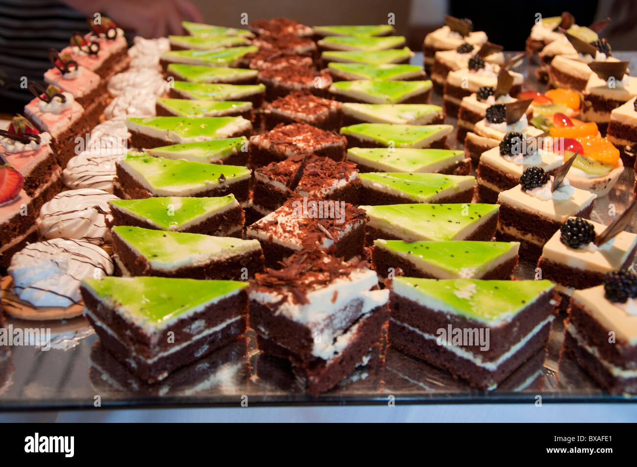 A large selection of colourful cakes on a glass shelf Stock Photo - Alamy