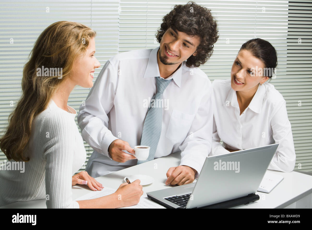Group of three young business people gathered together around the ...