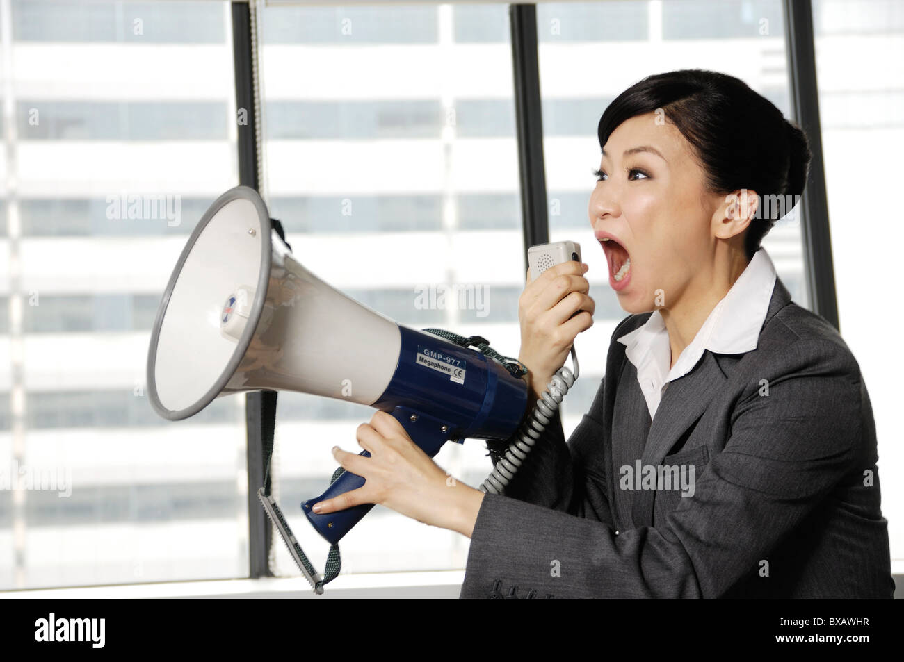 Businesswoman yelling through a megaphone in an office Stock Photo - Alamy