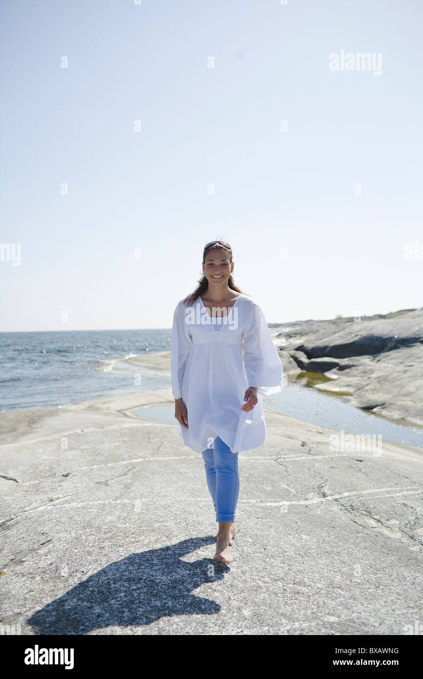 Woman walking on cliff next to sea Stock Photo - Alamy