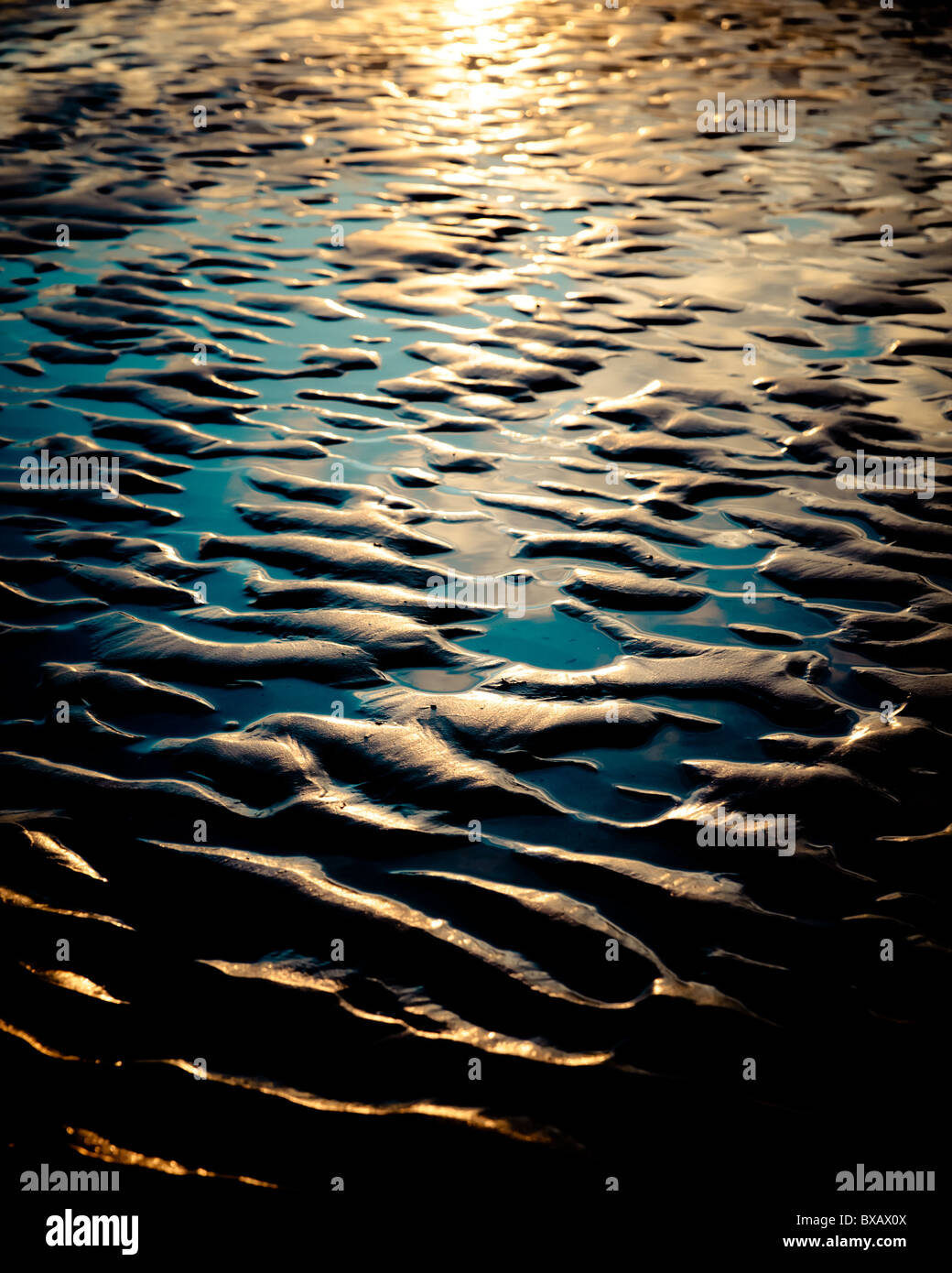 Ripples in the beach hold water reflecting the sunrise and the clouds ...