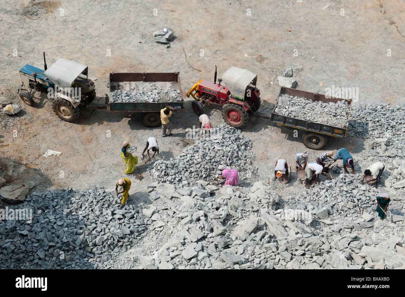 Tractors with trailers being loaded with broken rocks for the road ...