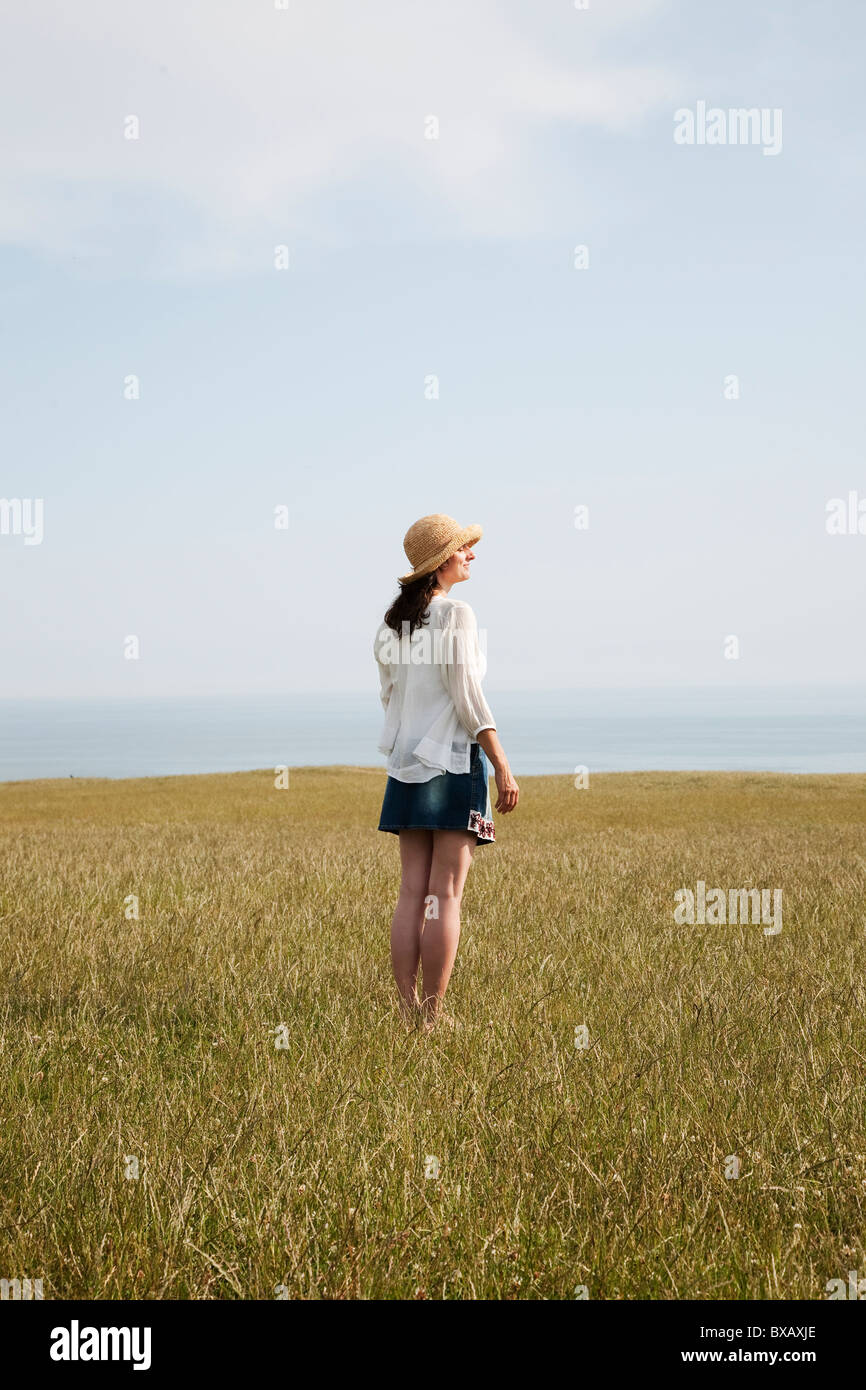 Woman standing in grass, looking at view Stock Photo - Alamy