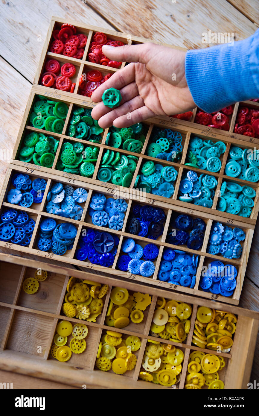 Persons hand browsing box of buttons Stock Photo - Alamy