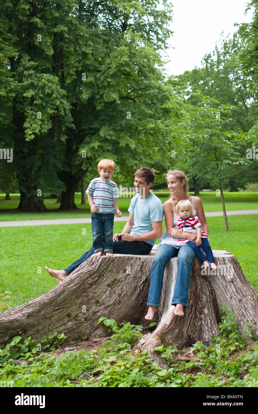 Mid adult couple with children sitting on stub in park and smiling ...