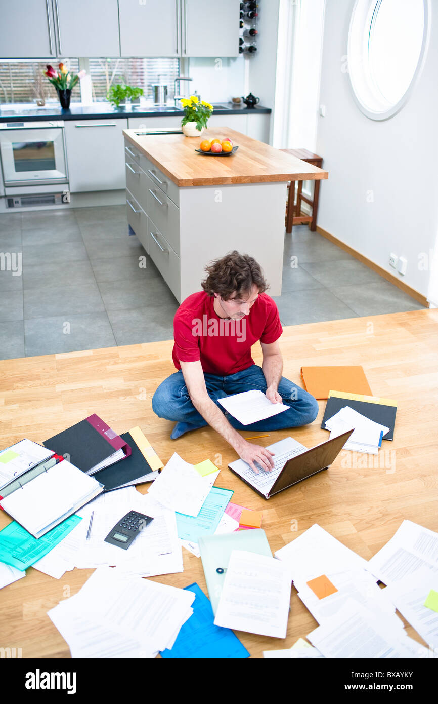 Elevated view of mid- adult man struggling with domestic paperwork ...
