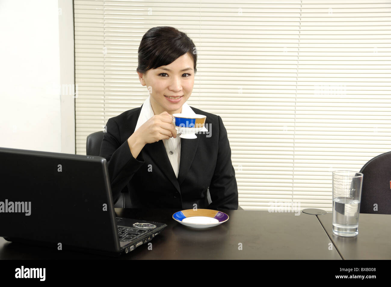 Businesswoman drinking tea in an office Stock Photo - Alamy