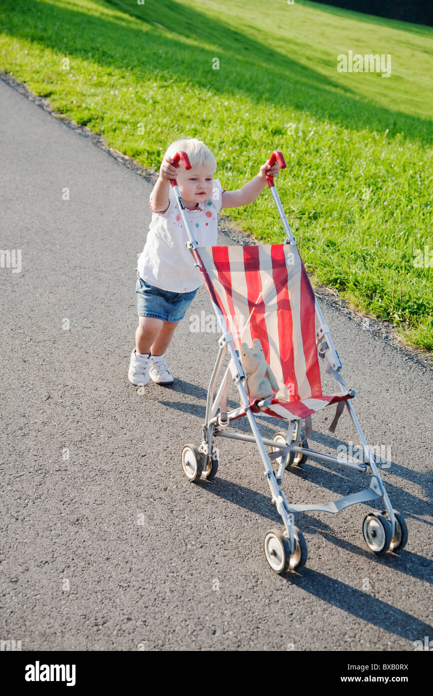 Girl pushing pushchair in park Stock Photo - Alamy