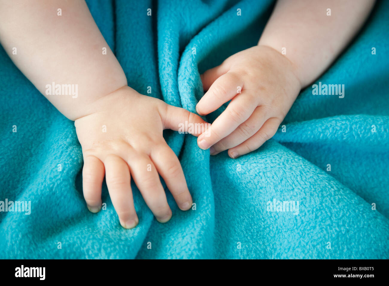 Close-up of babys hand on blue sheet Stock Photo - Alamy
