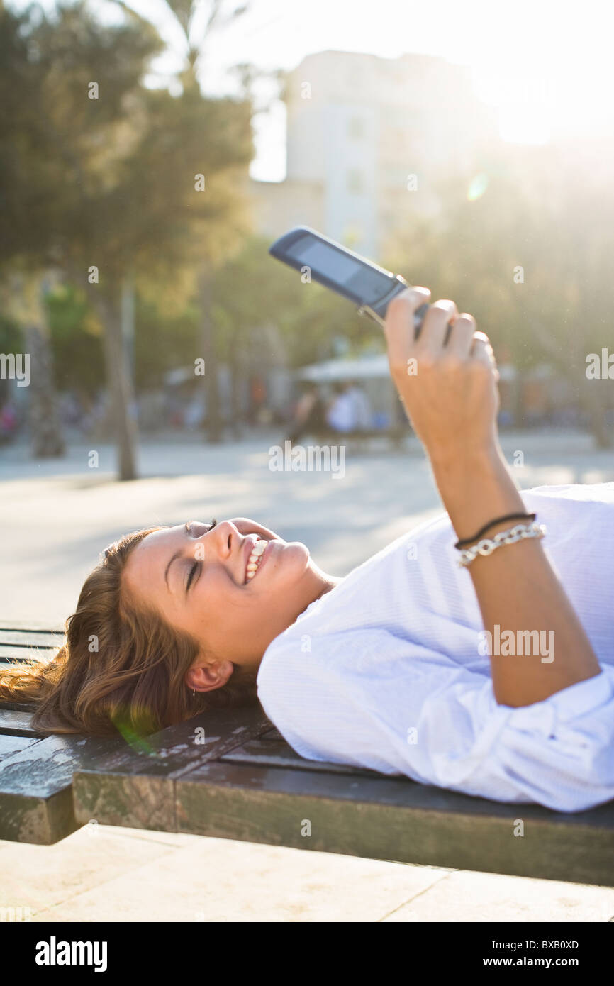 Girl lying on park bench, using cell phone Stock Photo - Alamy