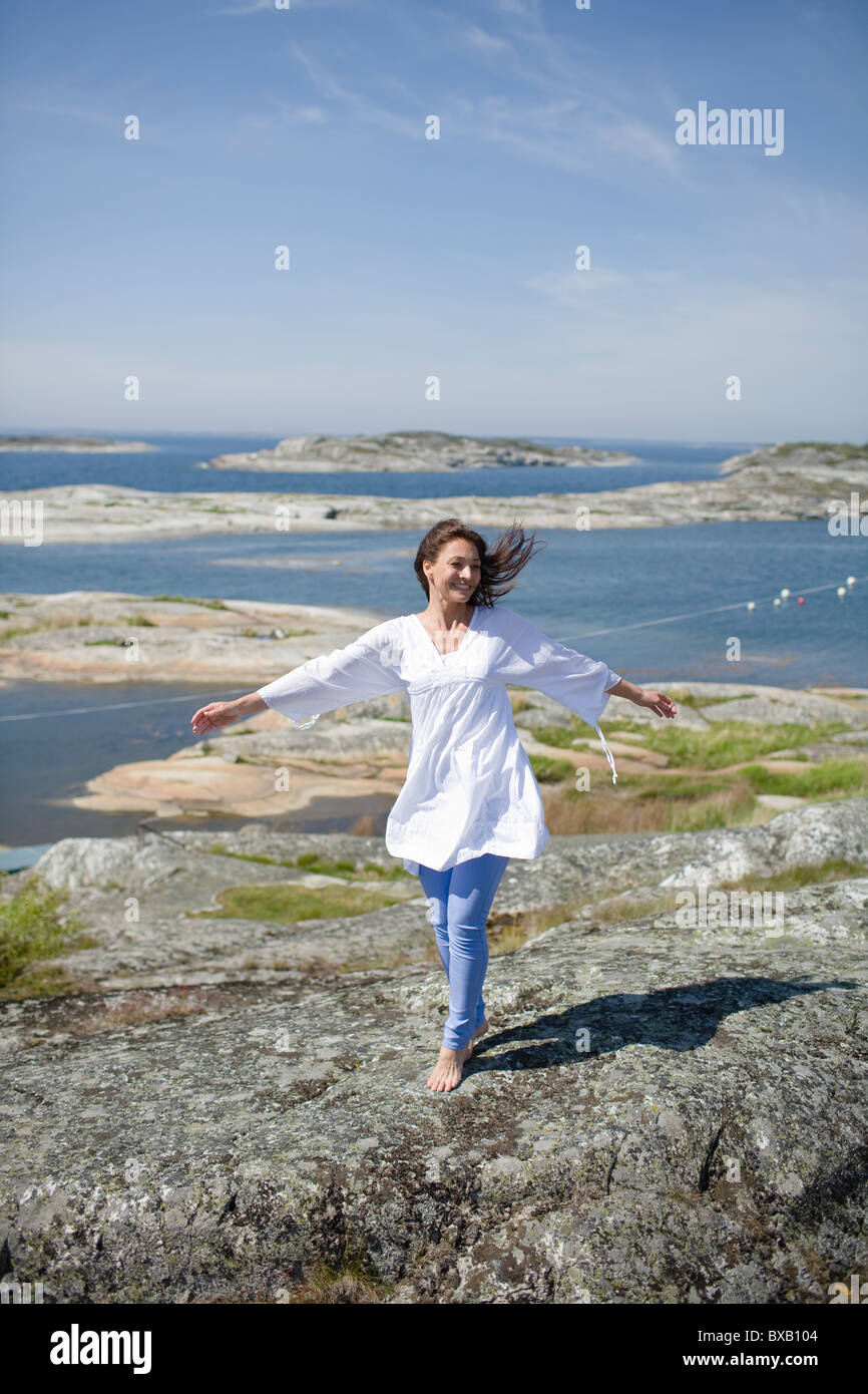 Woman walking on rock with arms up, smiling Stock Photo - Alamy