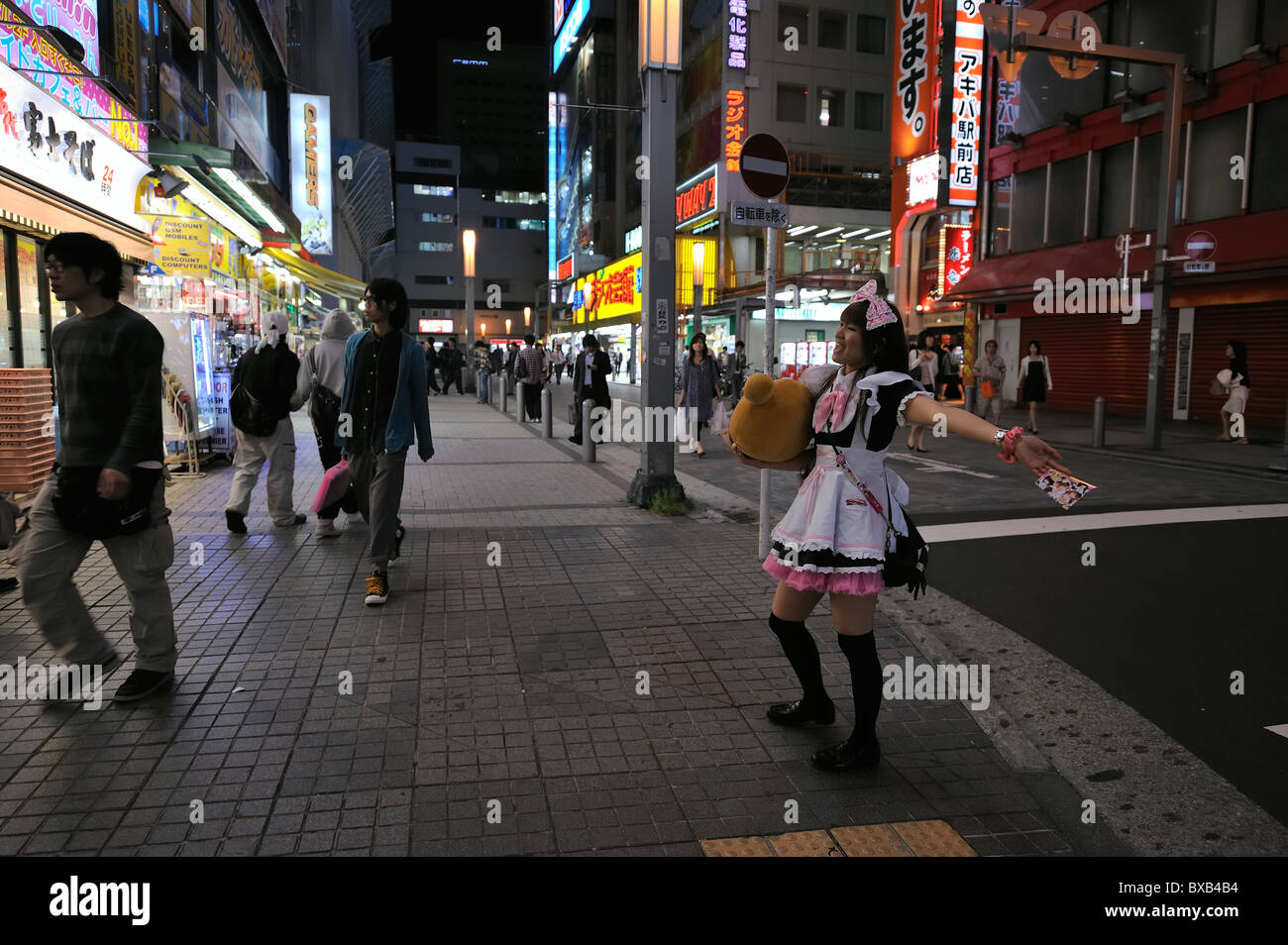 Young, Japanese woman promoting maid cafe in Akihabara at night, Tokyo ...