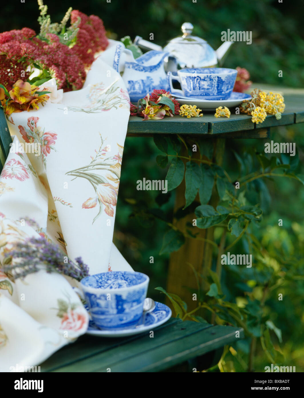 Still-Life of blue+white cups on table and chair with draped fabric ...
