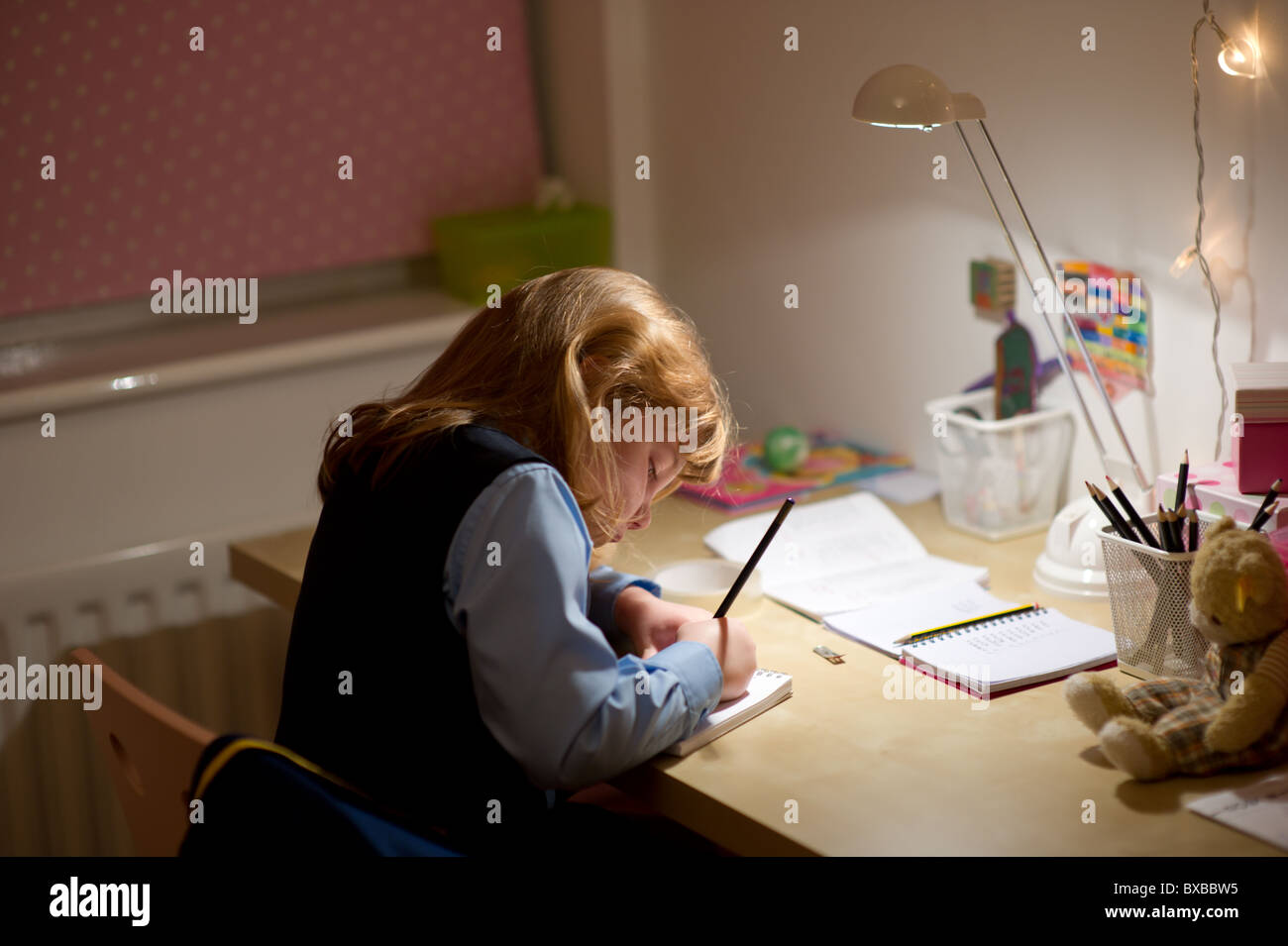 Young primary age girl sits at her desk to complete her homework Stock ...