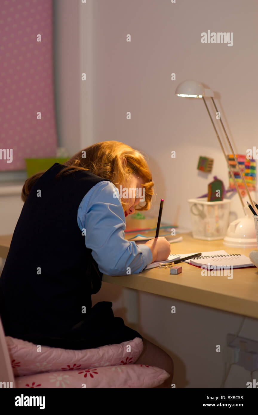 Young primary age girl sits at her desk to complete her homework Stock ...