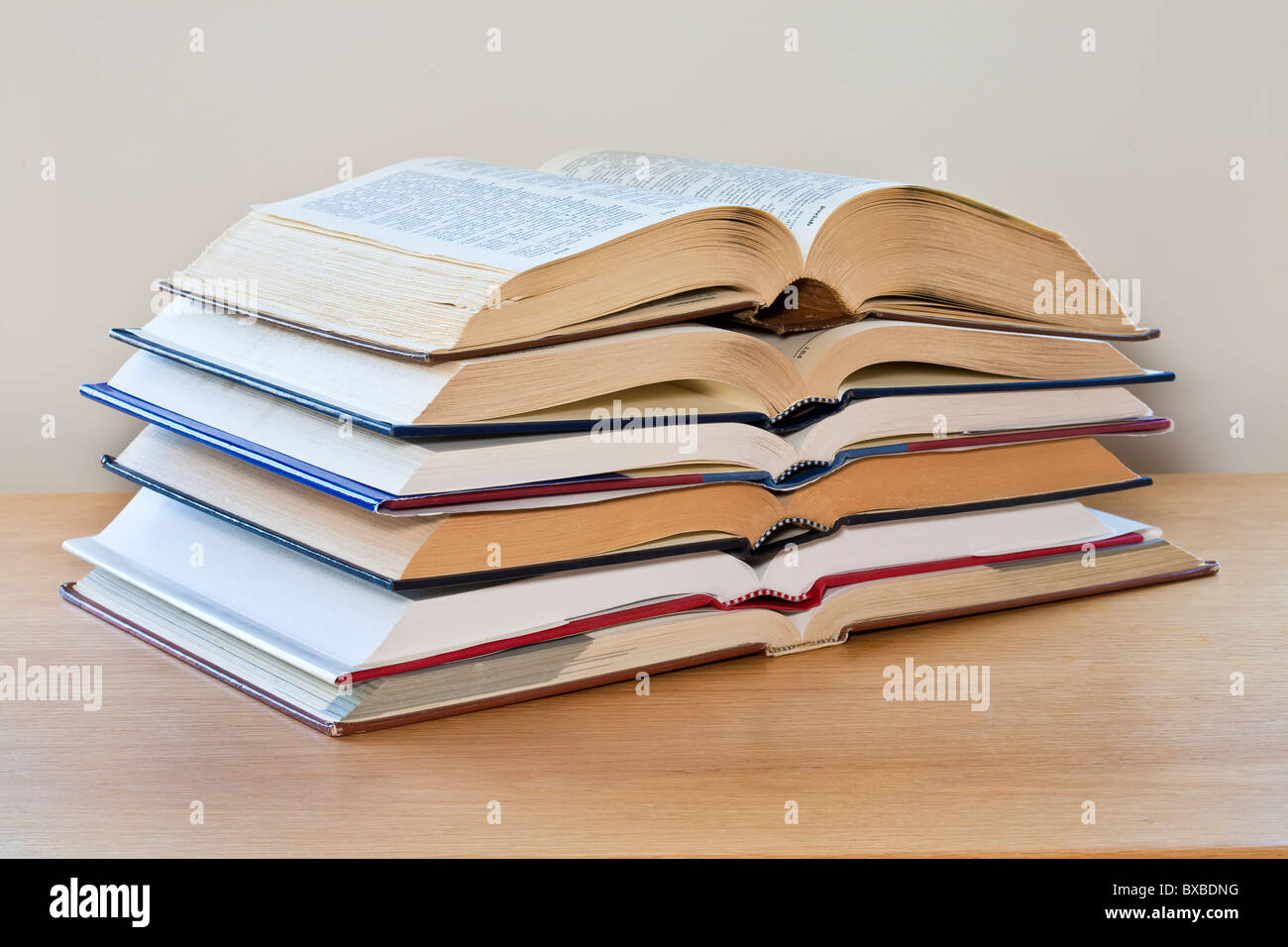 stack of open hardcover books on wooden desk Stock Photo - Alamy