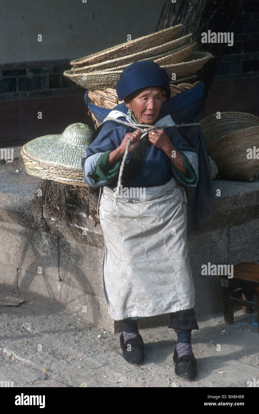 CHINA. NATIVE NAXI WOMAN CARRYING BASKETS IN LIJIANG, YUNNAN PROVINCE ...