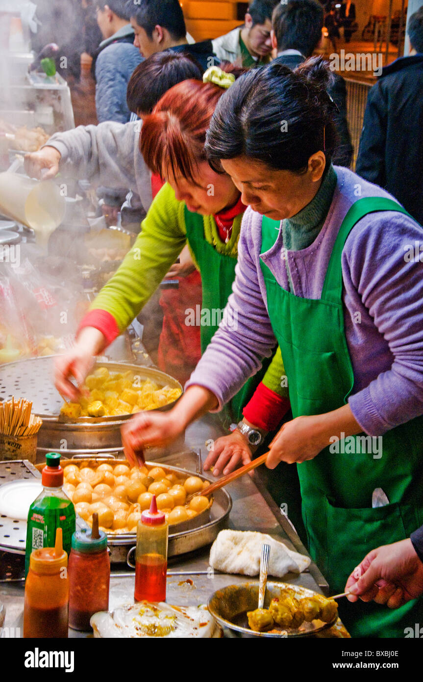 Asian women preparing food at outdoor food stall on city street in ...