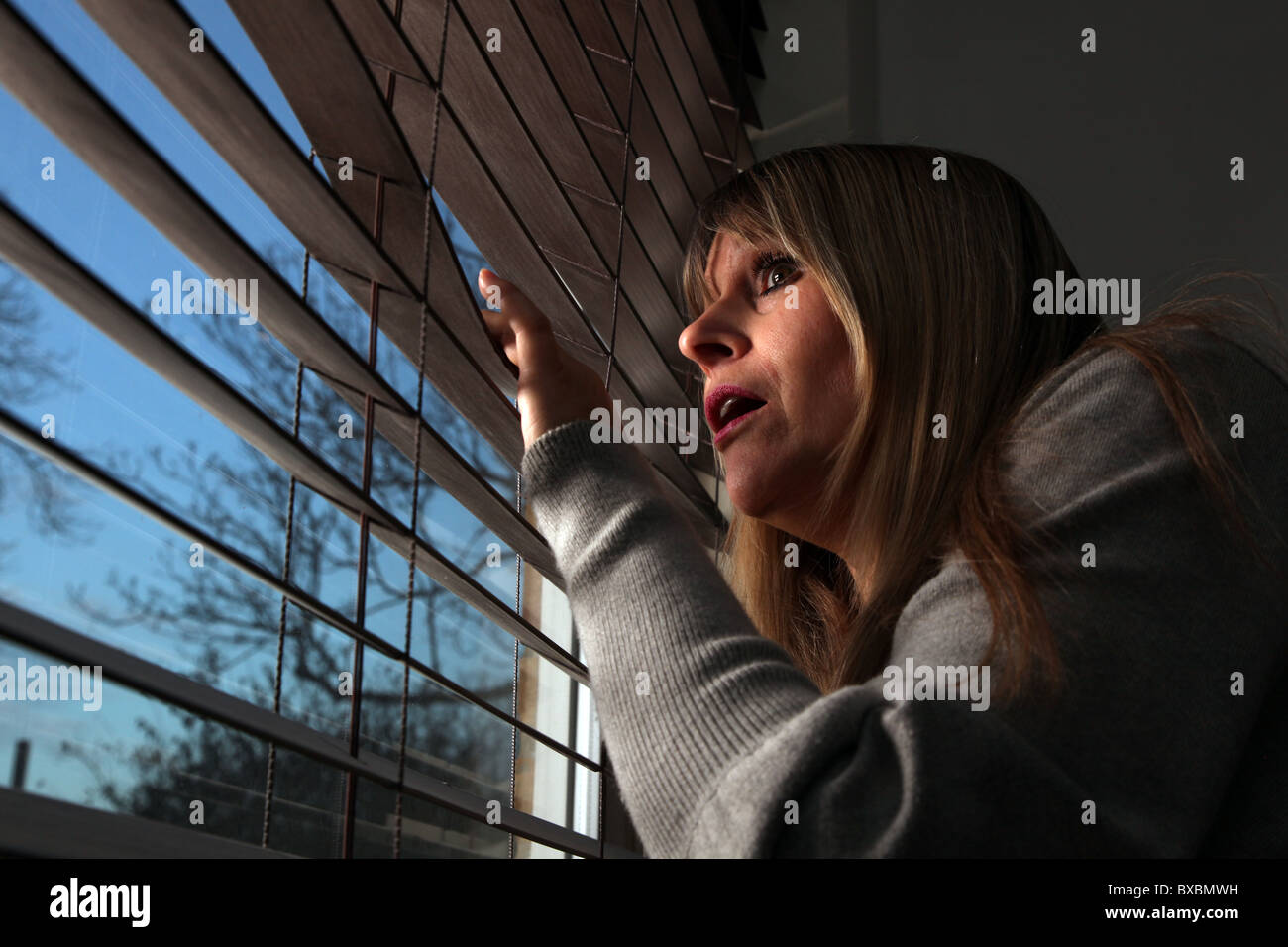 Woman looking through blinds scared hi-res stock photography and images ...
