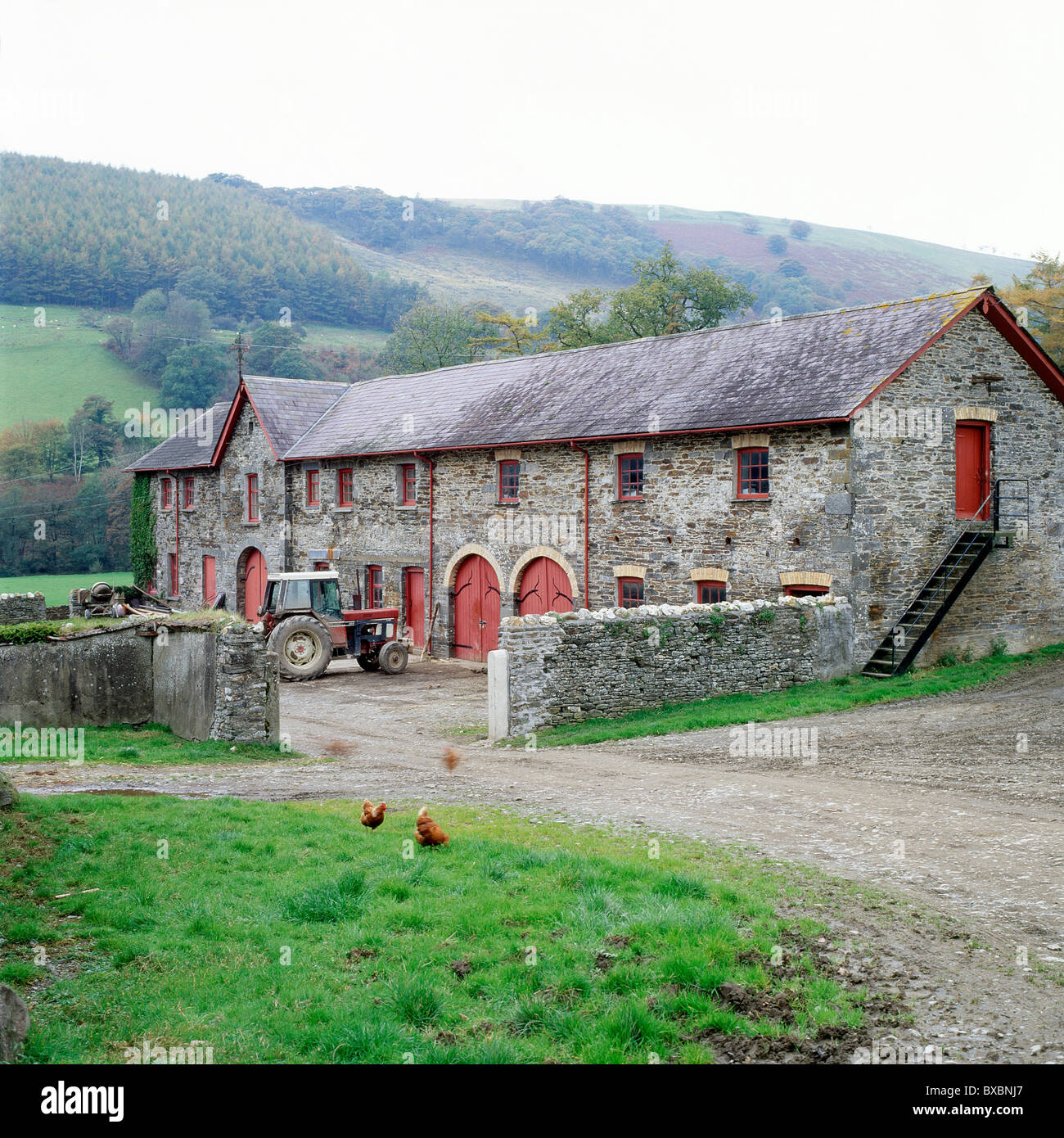 A long stone barn with red trim on doors, windows and arches ...