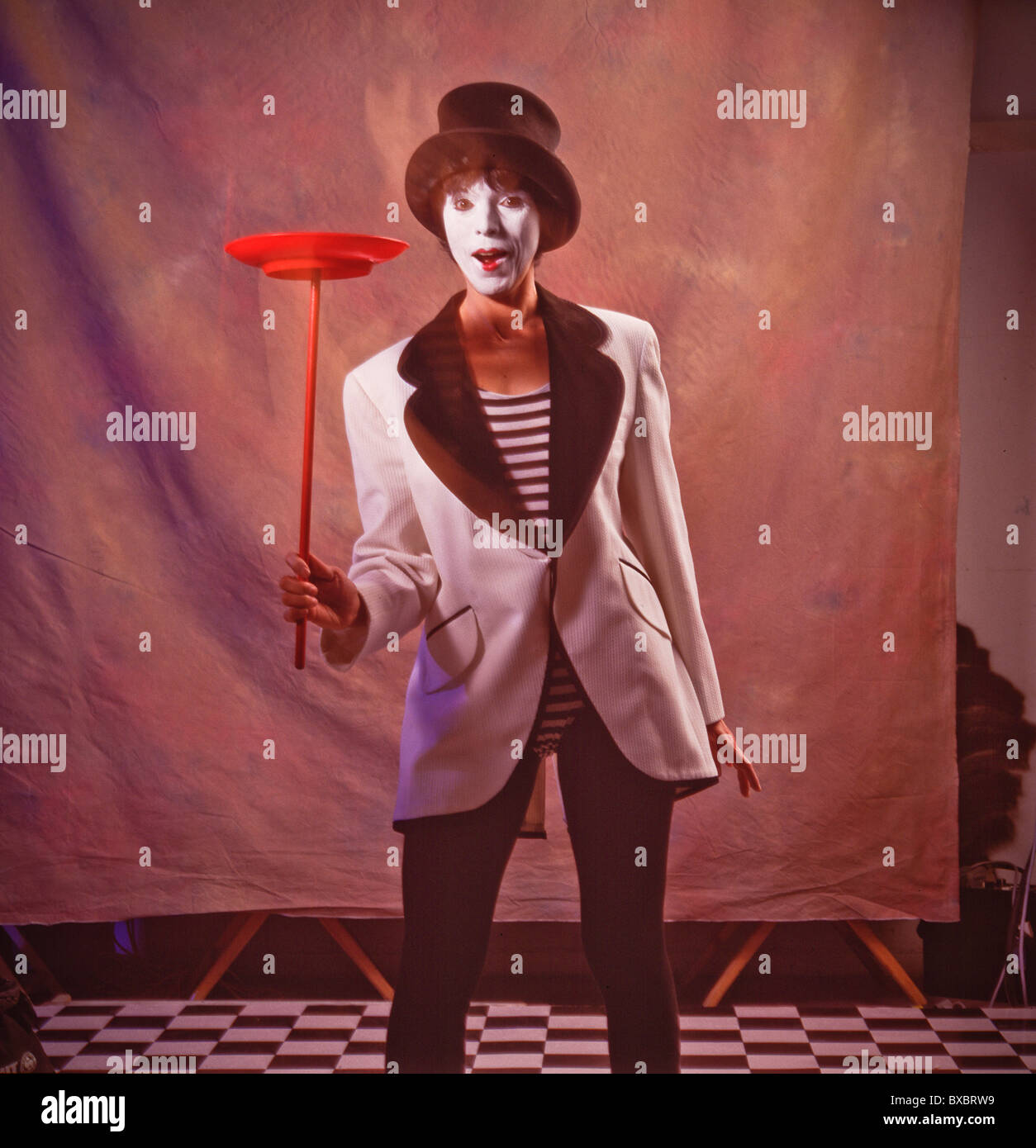 One female White face, faced, top hat mime performs plate twirl spin ...