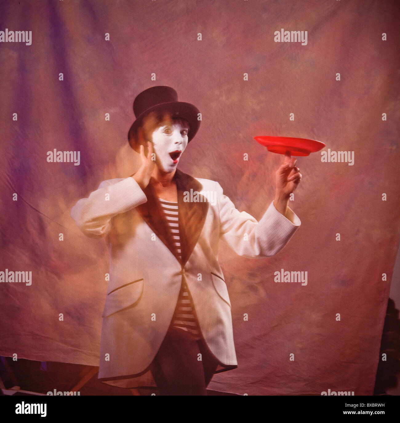 One female White face, faced, top hat mime performs plate twirl spin ...